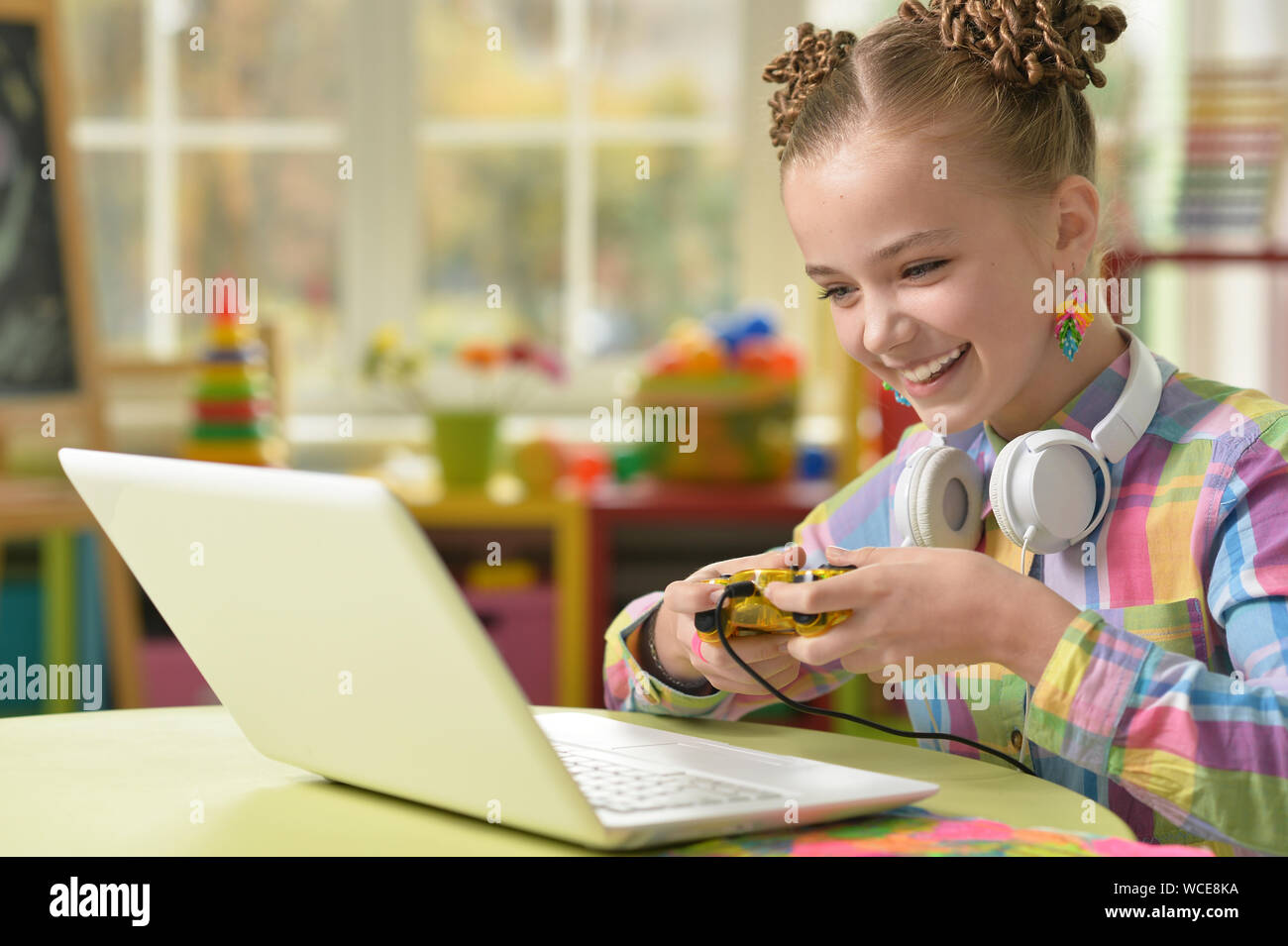 Portrait of cute little girl sitting at the table and playing computer ...