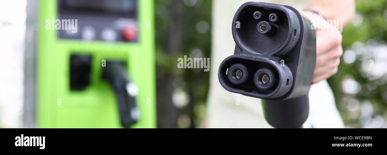 Male hand holding black car charging car cable Stock Photo - Alamy