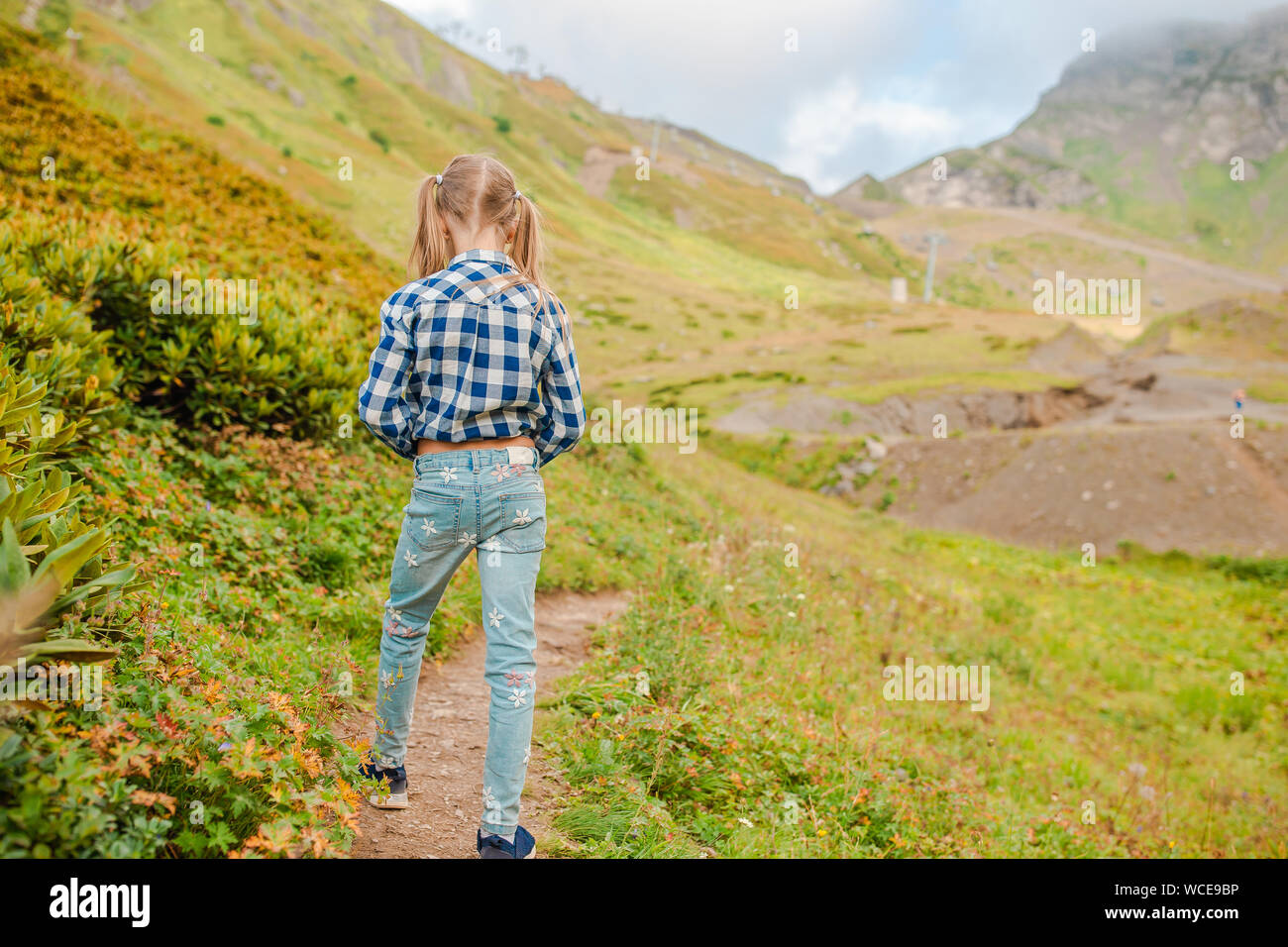 Adorable happy little girl in mountains in the background of beautful ...