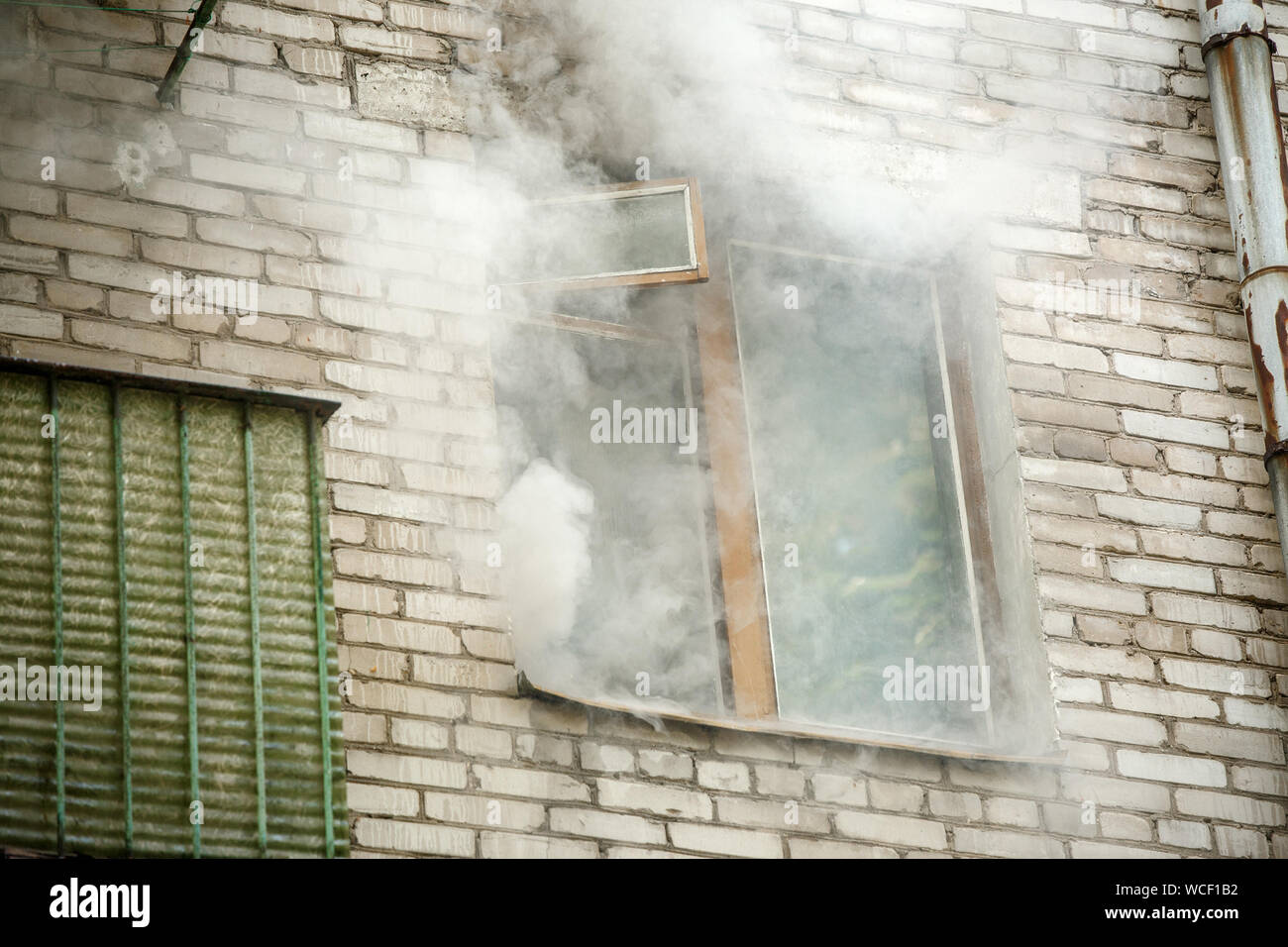 Photo of brick house with smoke coming out of window during day Stock ...