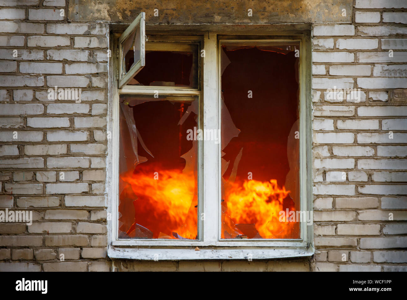Picture of brick house with with fire in window during day Stock Photo ...