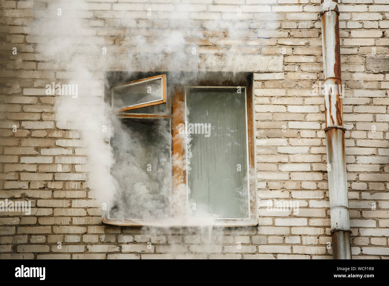Picture of brick house with smoke coming out of window during day Stock ...
