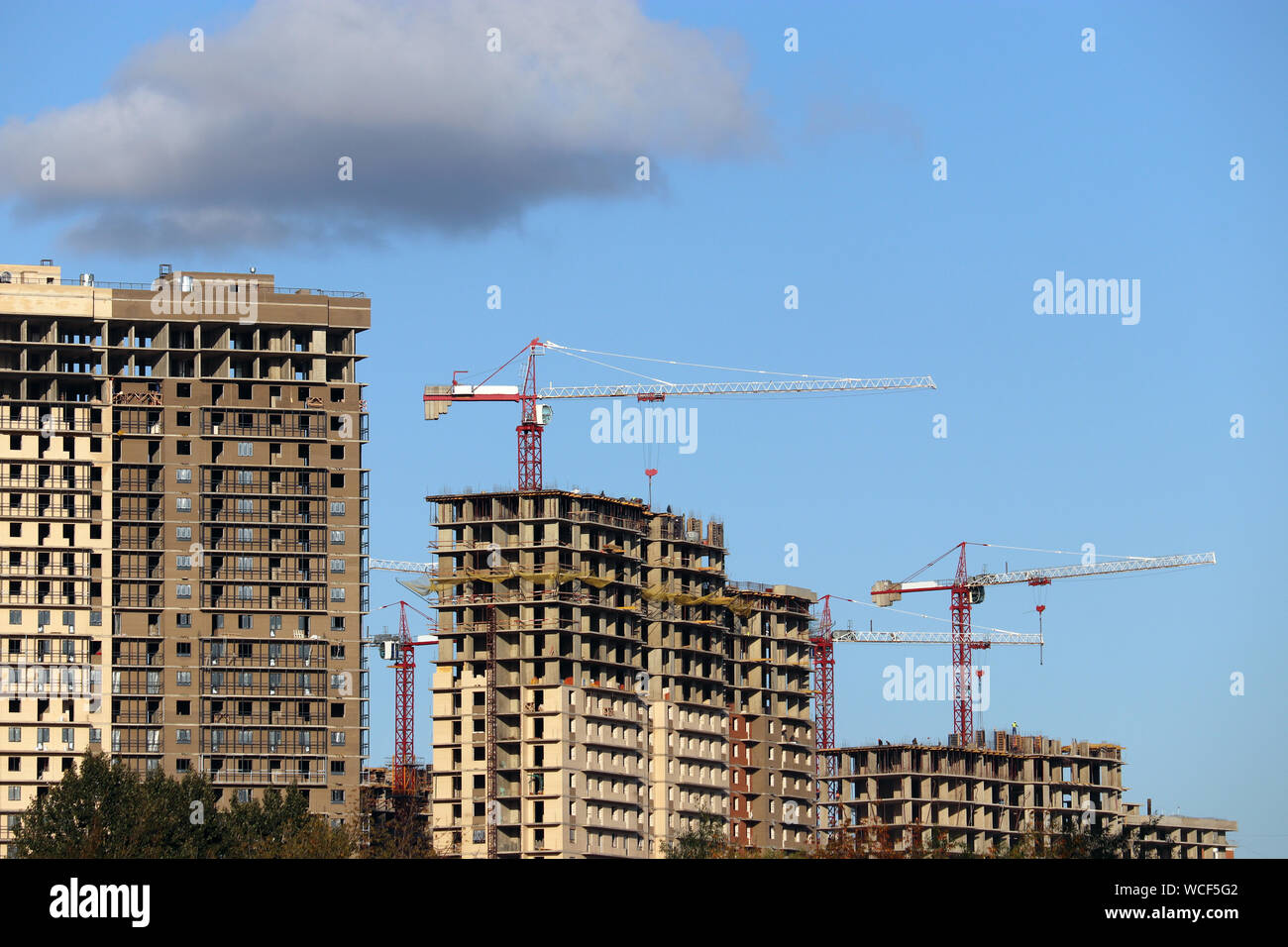 Construction cranes and unfinished high-rise residential buildings on ...