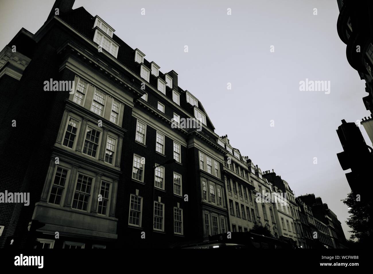 Wide low angle grayscale shot of buildings with windows next to each ...