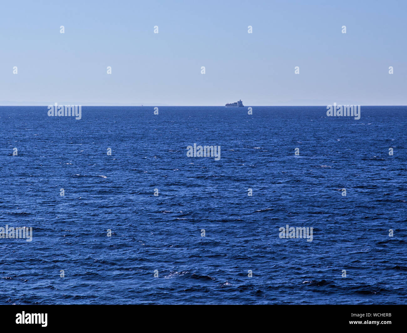 Distant cargo ship sailing at textured sea Stock Photo - Alamy