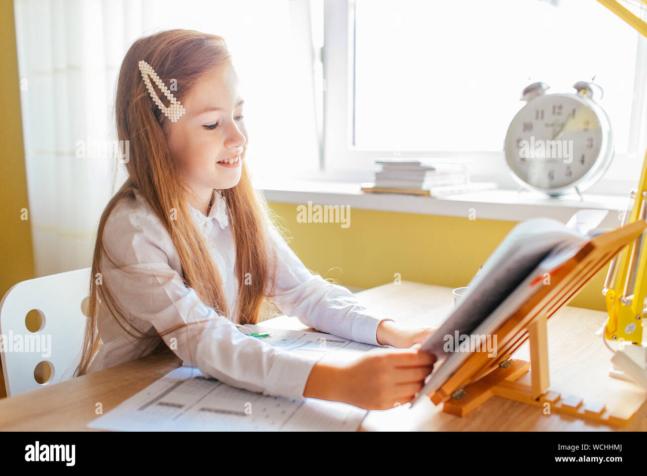 Education at home concept - Cute little girl with long hair studying or completing home work on ...
