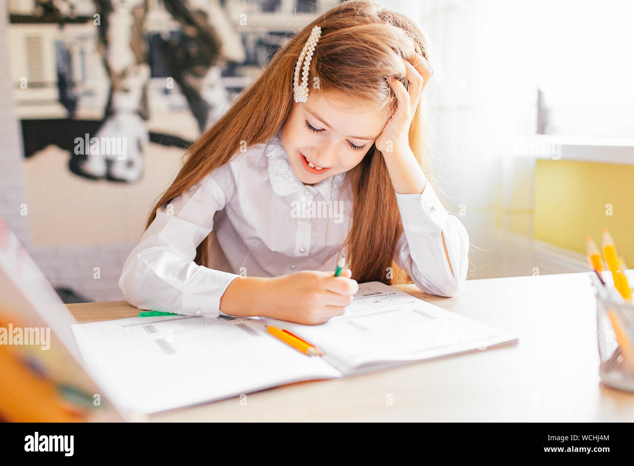 Education at home concept - Cute little girl with long hair studying or completing home work on ...