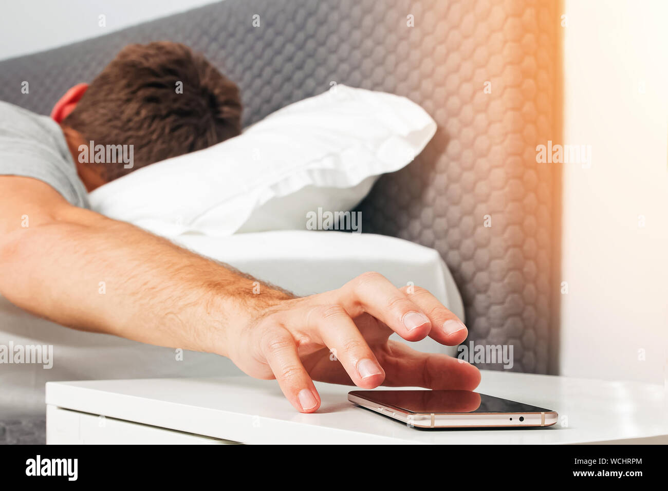 Man's hand close-up trying to reach out ringing cell phone or alarm to ...