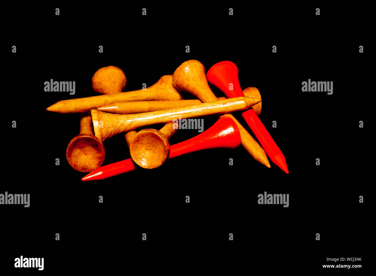 Pile of wooden golf tee pegs on a black background Stock Photo - Alamy