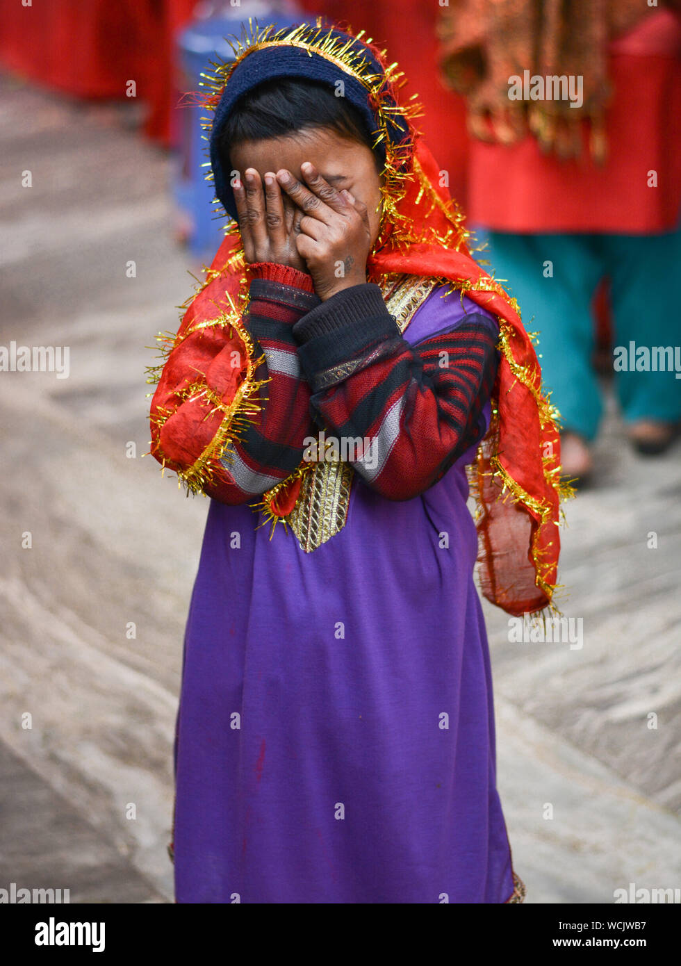 Girl child beggar giving expressions at camera in colorful religious ...