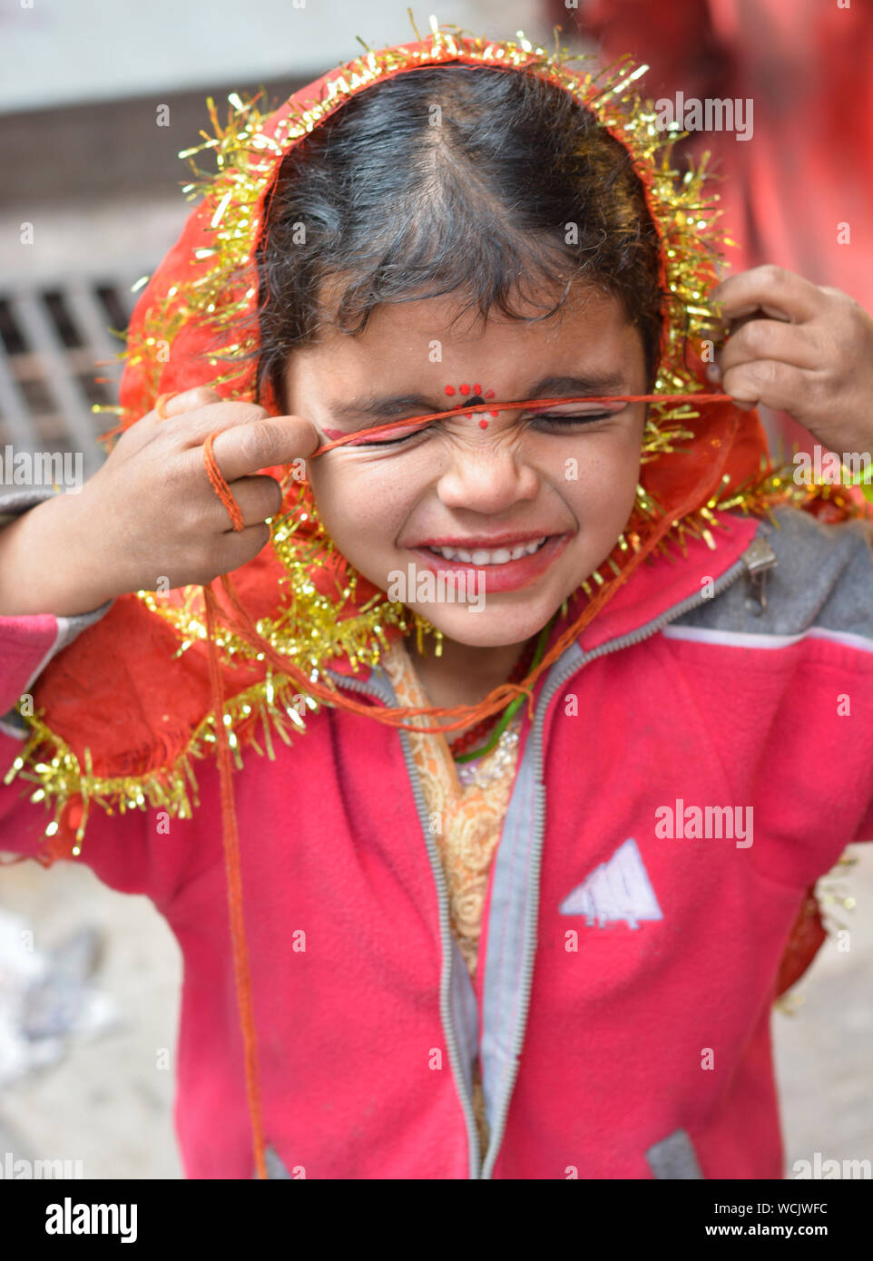 Girl child beggar giving expressions at camera in colorful religious ...