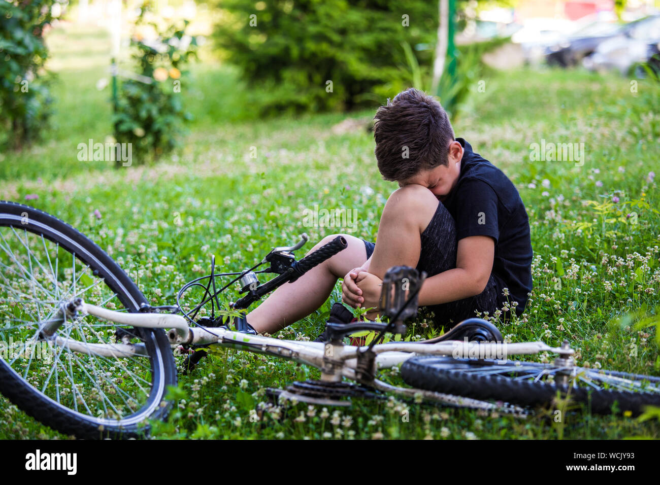 Boy in the street ground with a knee injury screaming after falling off ...