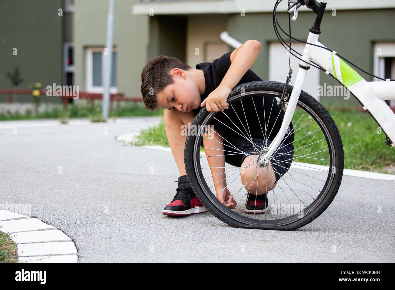 Sad boy looking at his flat bike tire, kid staring at the bicycle with ...