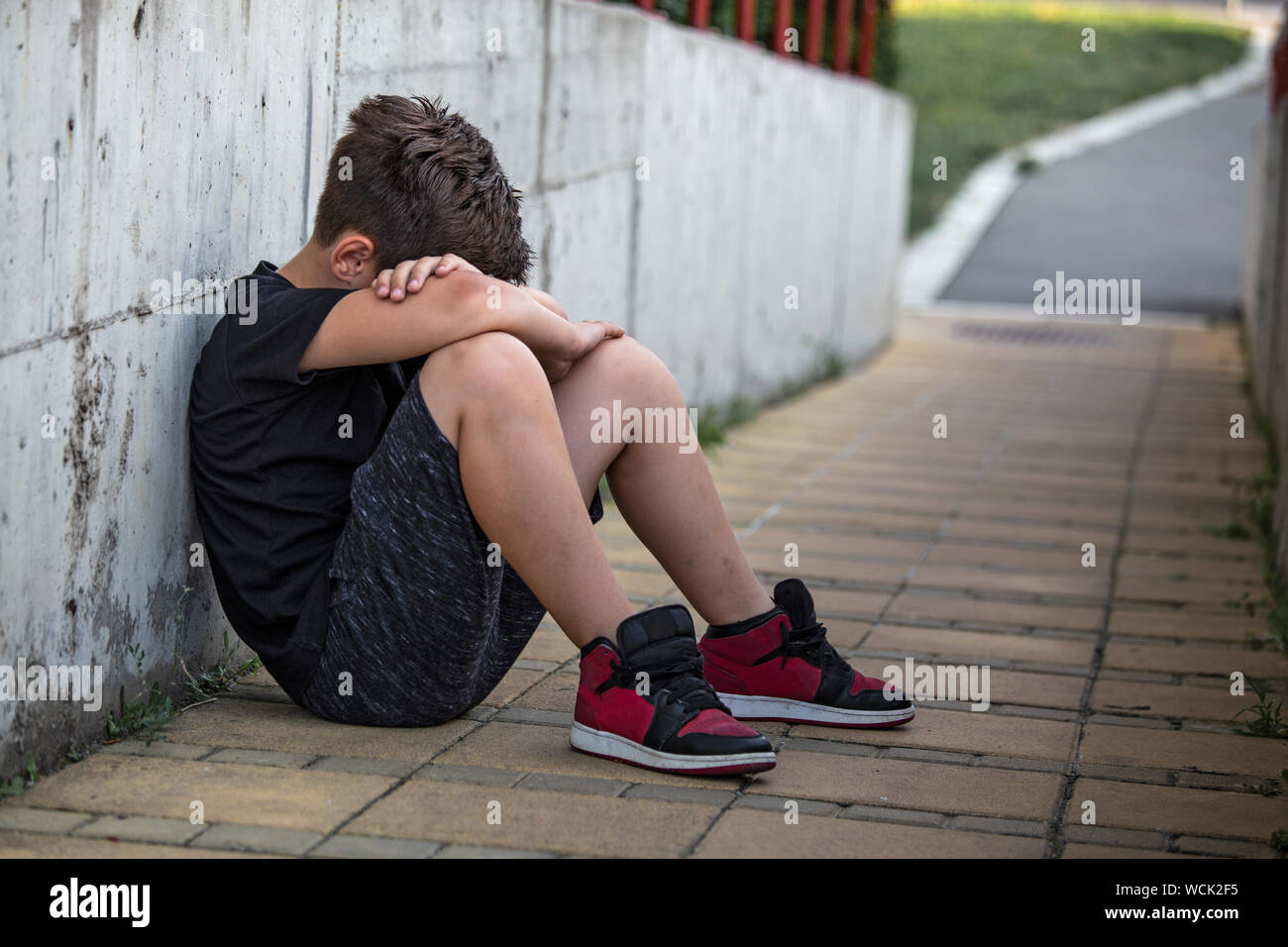 Little boy sad sitting alone at school hides his face. Isolation and ... Little boy sad sitting alone at school hides his face. Isolation and ...
