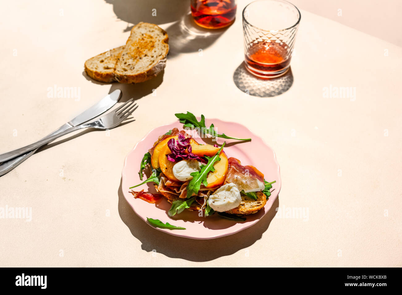 Parma ham, mozzarella and peaches sandwich on a plate, some bread and ...