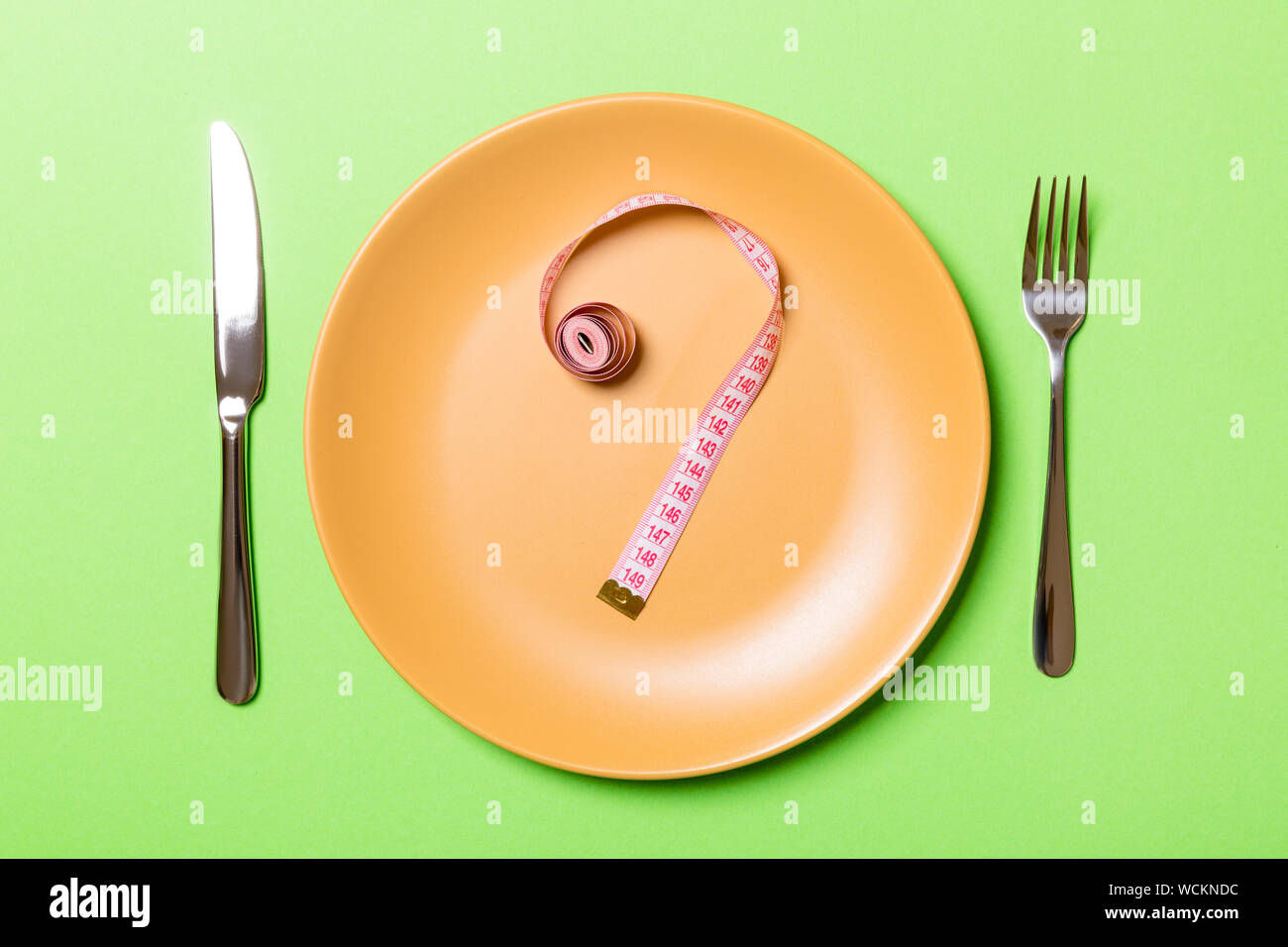 Question mark made of measuring tape on round plate on green background ...