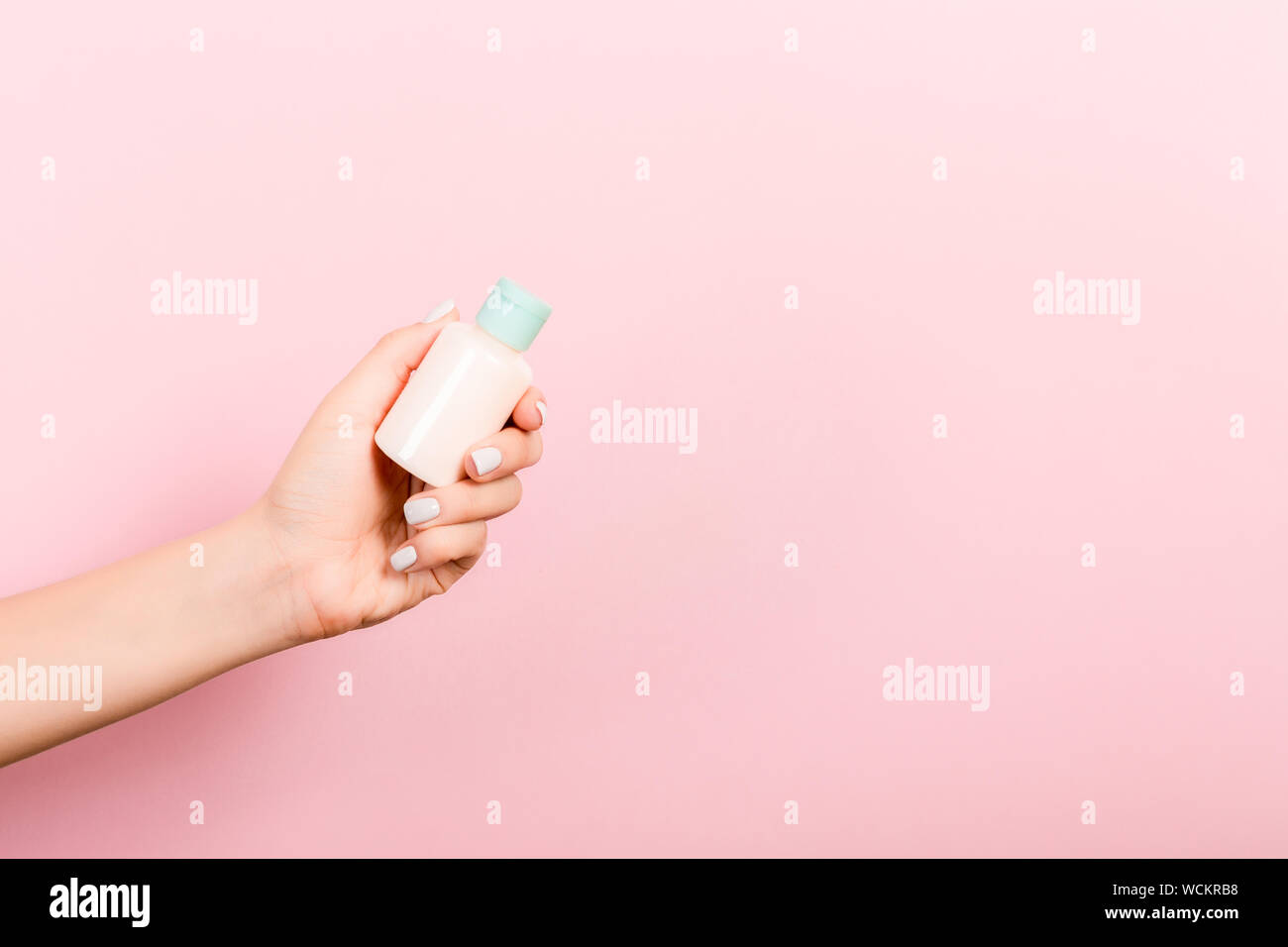 Female hand holding cream bottle of lotion isolated. Girl give tube ...