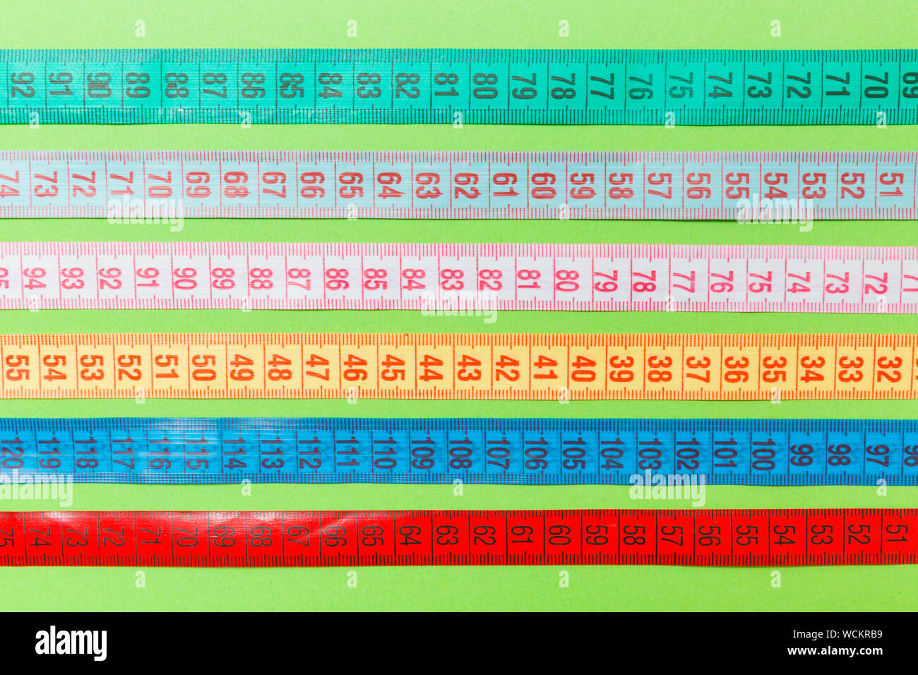 Close up of a group of colorful measure tapes lying in rows as a ...