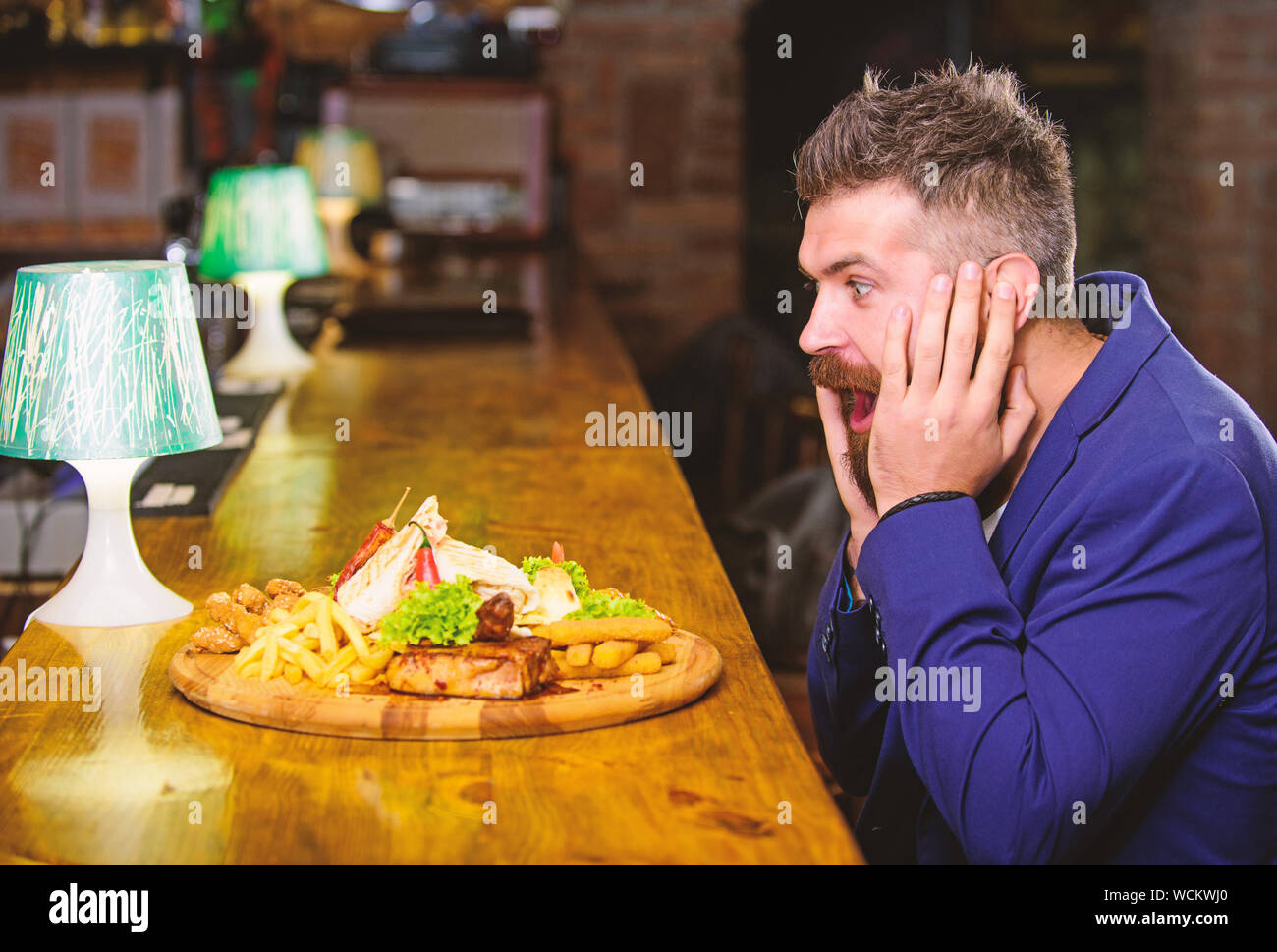 Hipster formal suit sit at bar counter. Man received meal with fried ...