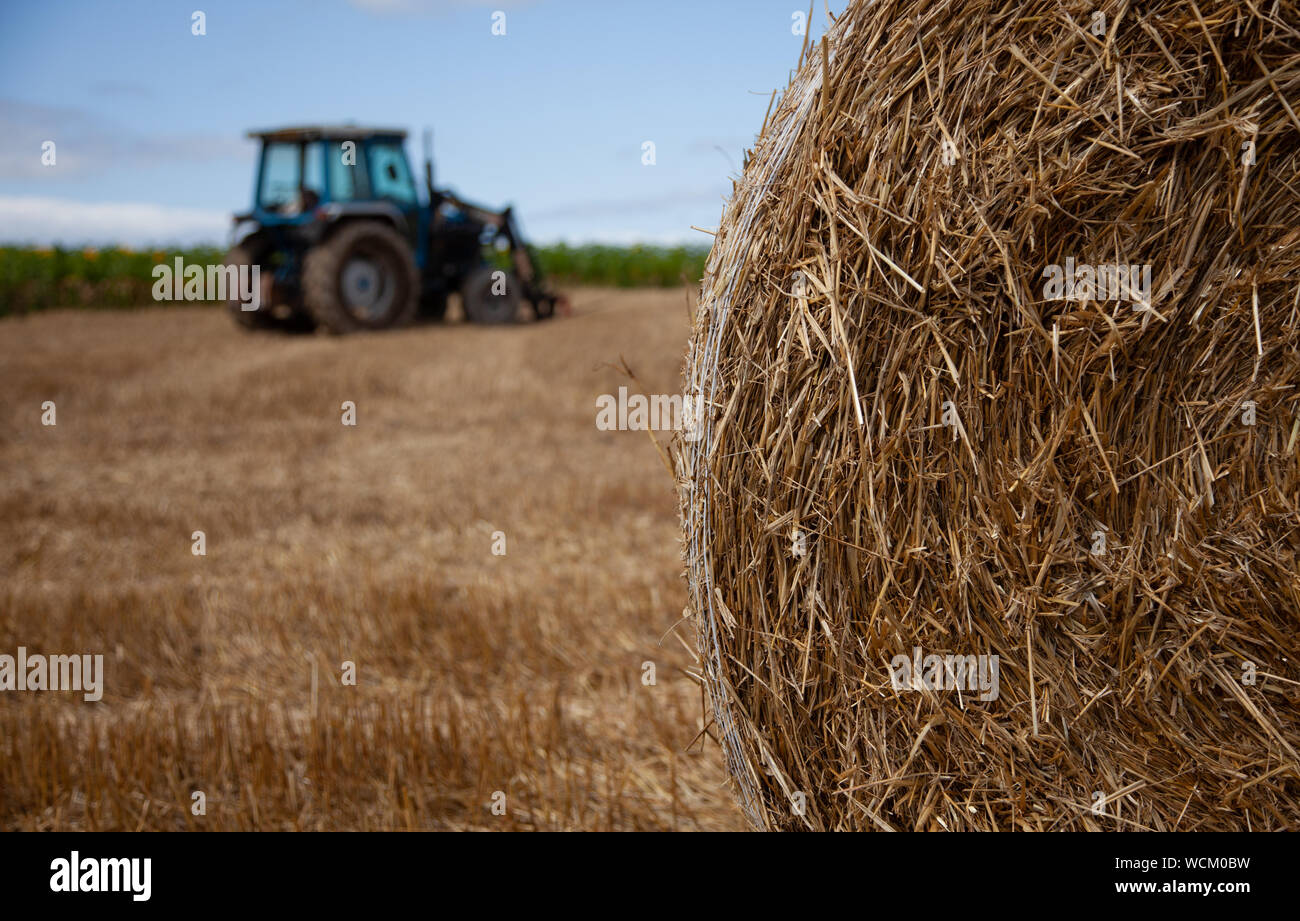 Hay bale and tractor at harvest time Stock Photo - Alamy