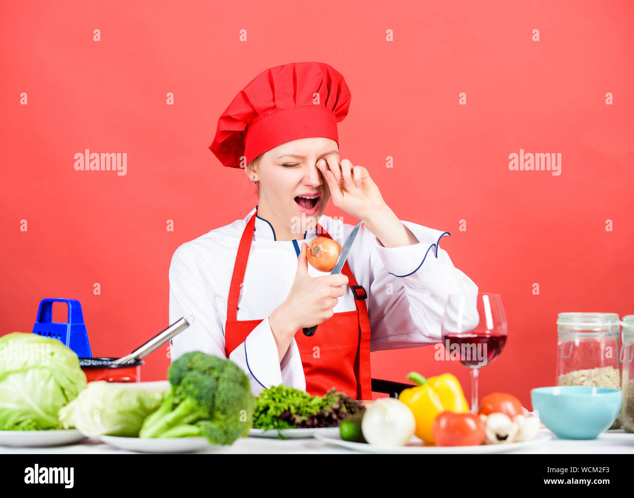 woman in cook hat crying because of onion. professional chef on red ...