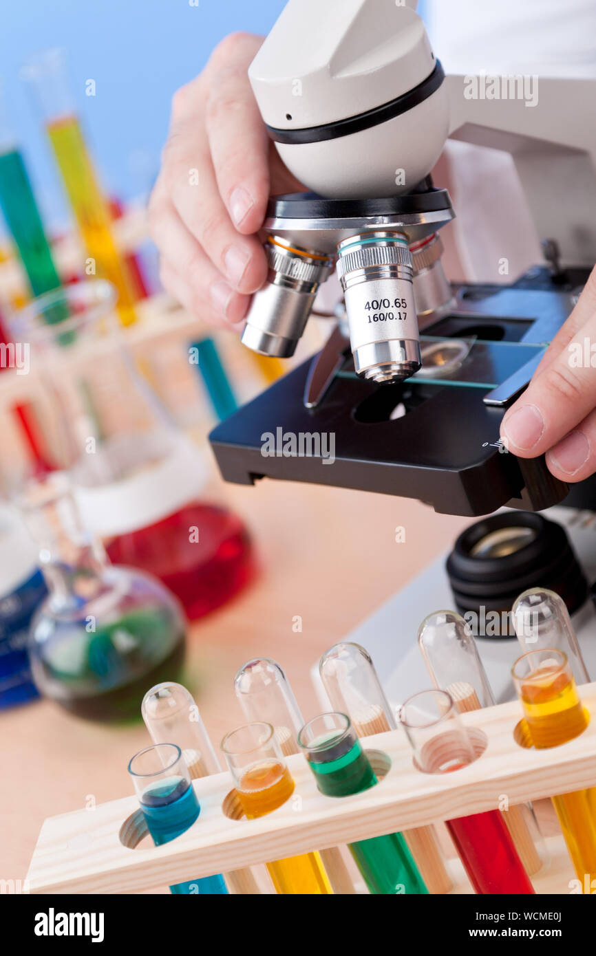 Medical or scientific researcher using a microscope in a lab or ...