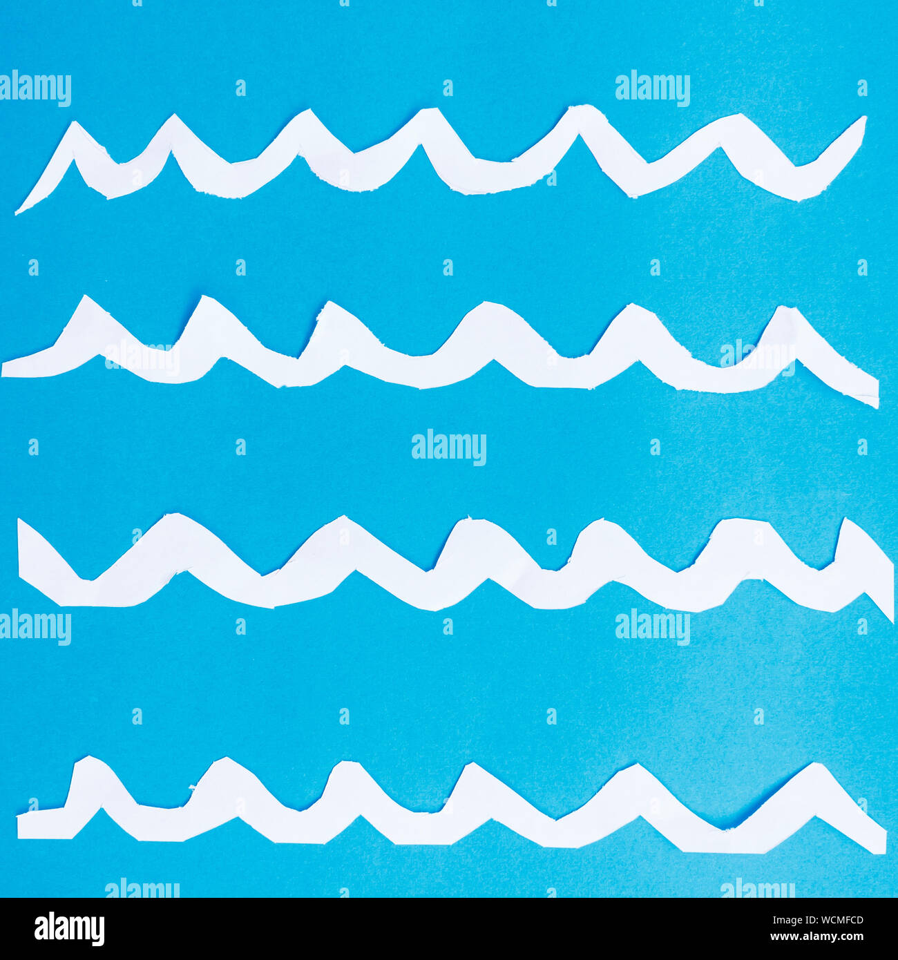 a set of paper waves on a blue surface represent the surface of the sea ...
