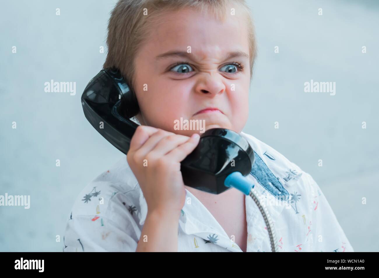 Cute closeup shot of an angry baby boy with black telephone Stock Photo ...
