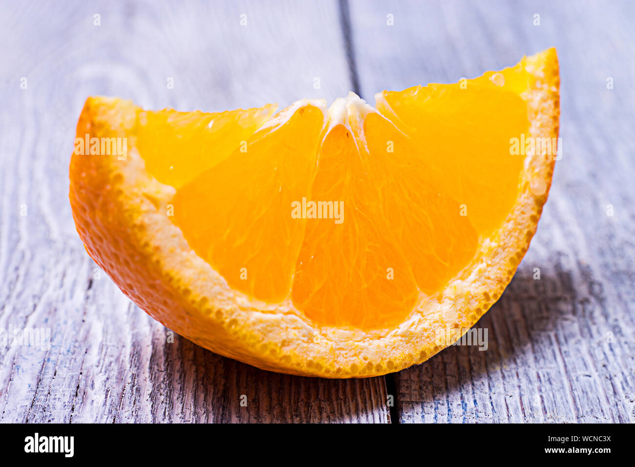 Ripe juicy orange wedge on rustic wood table top Stock Photo - Alamy