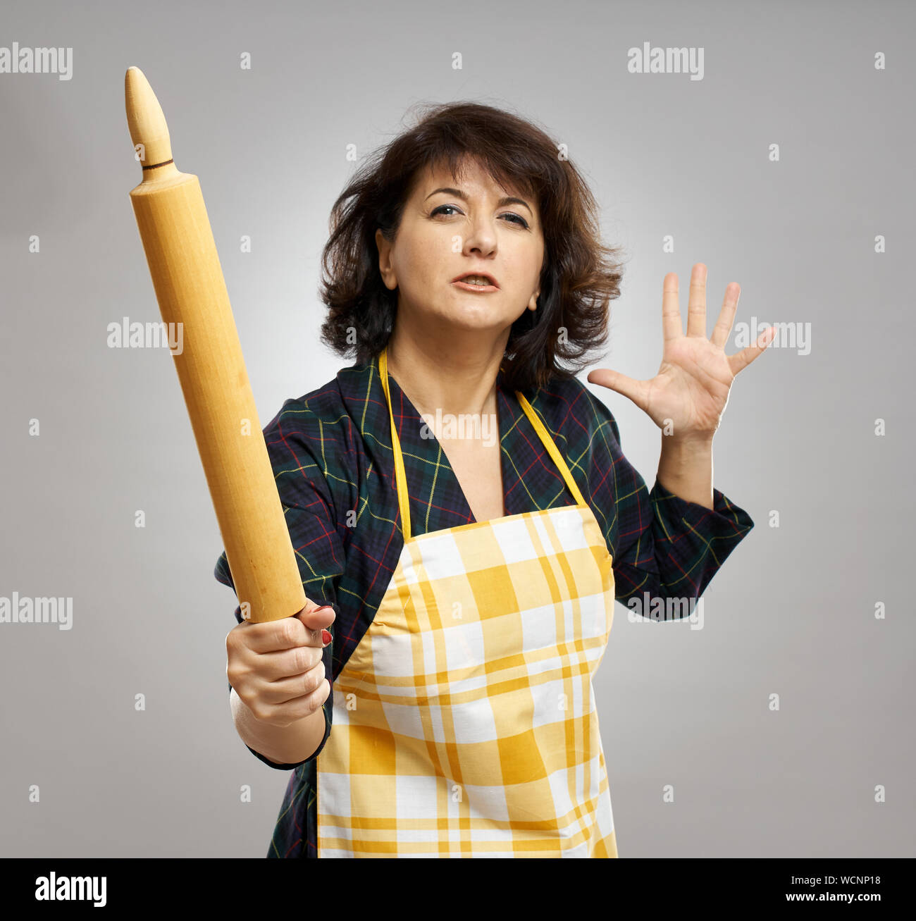 Baker lady with a wooden rolling pin over gray background Stock Photo ...