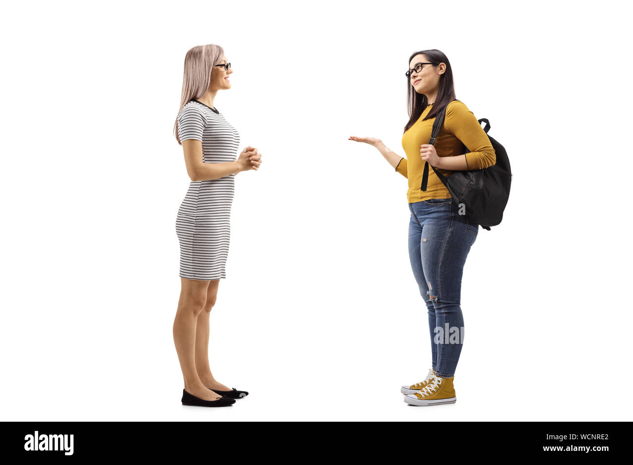 Full length shot of two young females having a conversation isolated on ...
