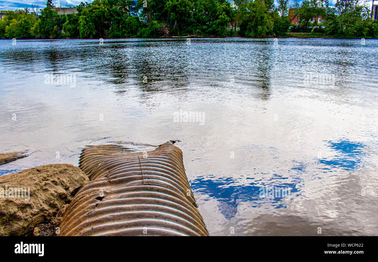 A drainage pipe releases its contents into the water of a very ...