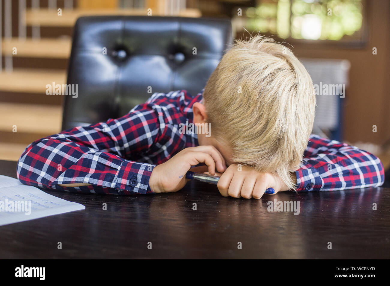 Sad schoolboy writing to notebook at home. Homework. Education ...