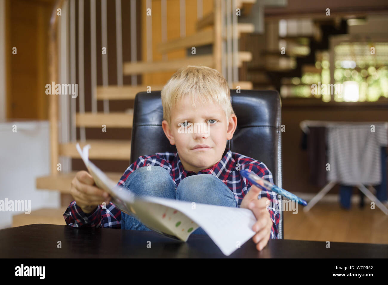 Sad schoolboy writing to notebook at home. Homework. Education ...