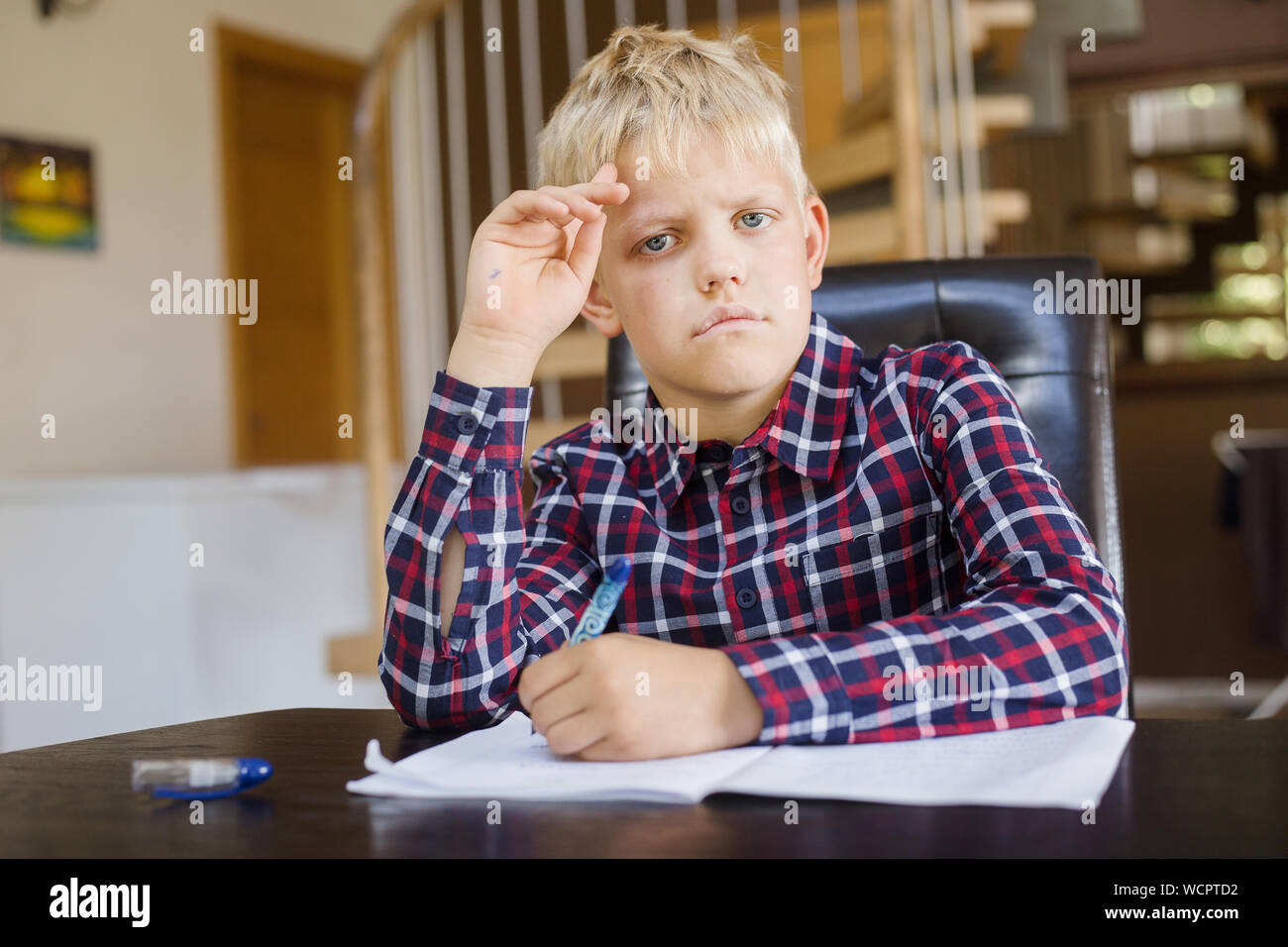 Sad schoolboy writing to notebook at home. Homework. Education ...
