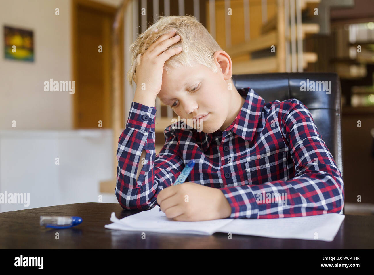 Sad schoolboy writing to notebook at home. Homework. Education ...