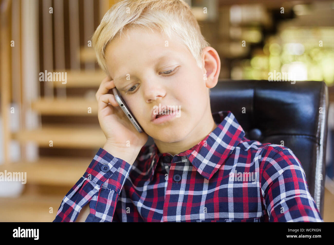 Cute little caucasian boy in a shirt talking on the phone. Modern ...