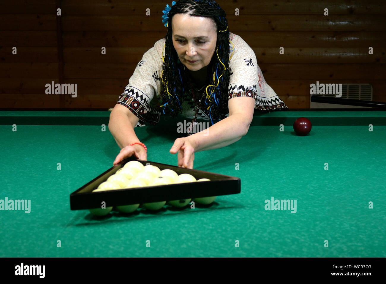 Senior woman put the balls in triangle of billiard balls on billiard ...