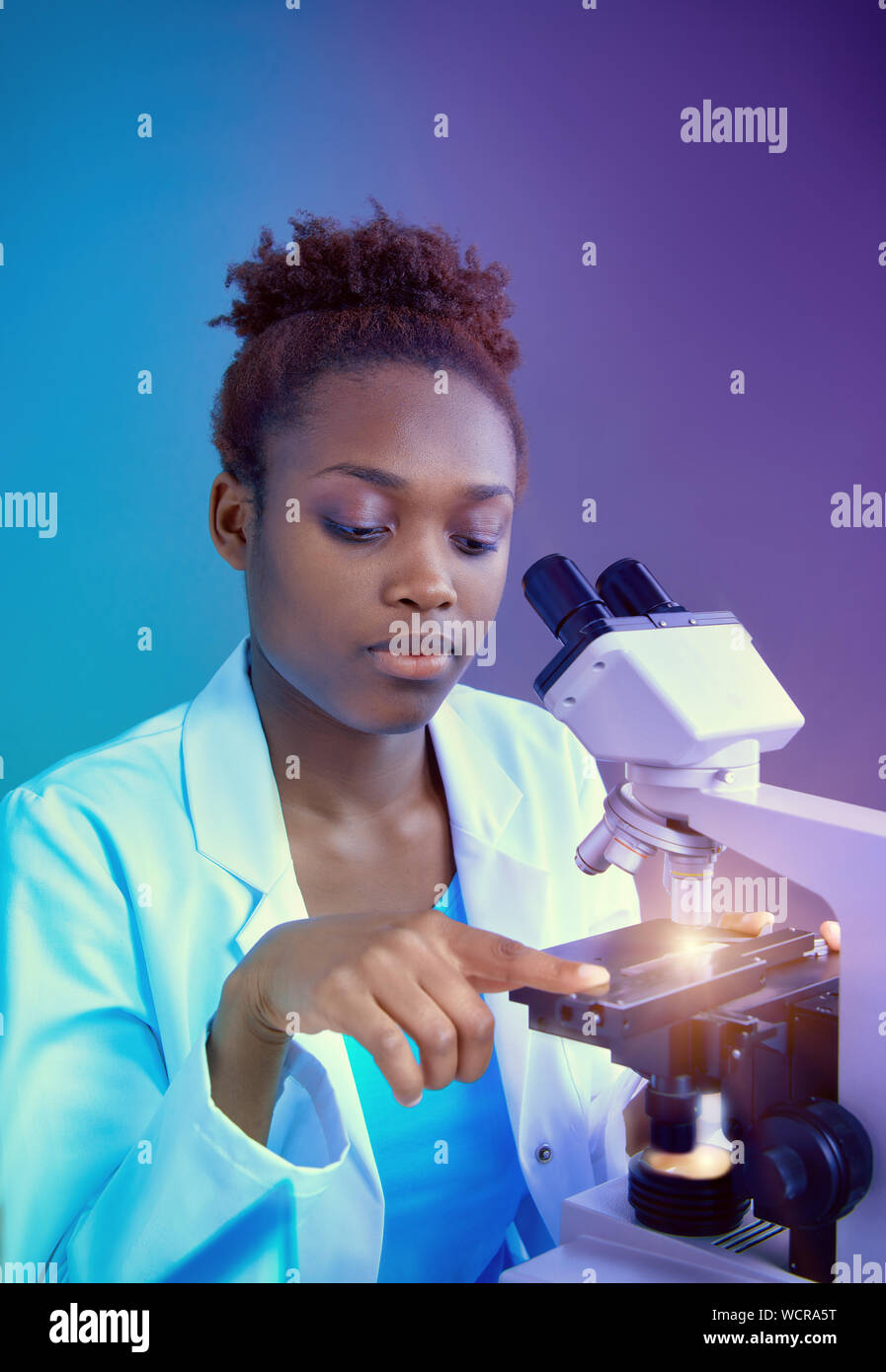 African scientist or graduate student in lab coat working with modern ...