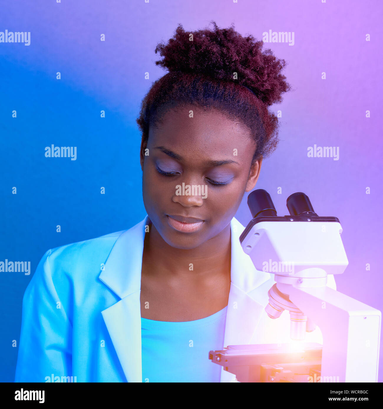African scientist or graduate student in lab coat working with modern ...