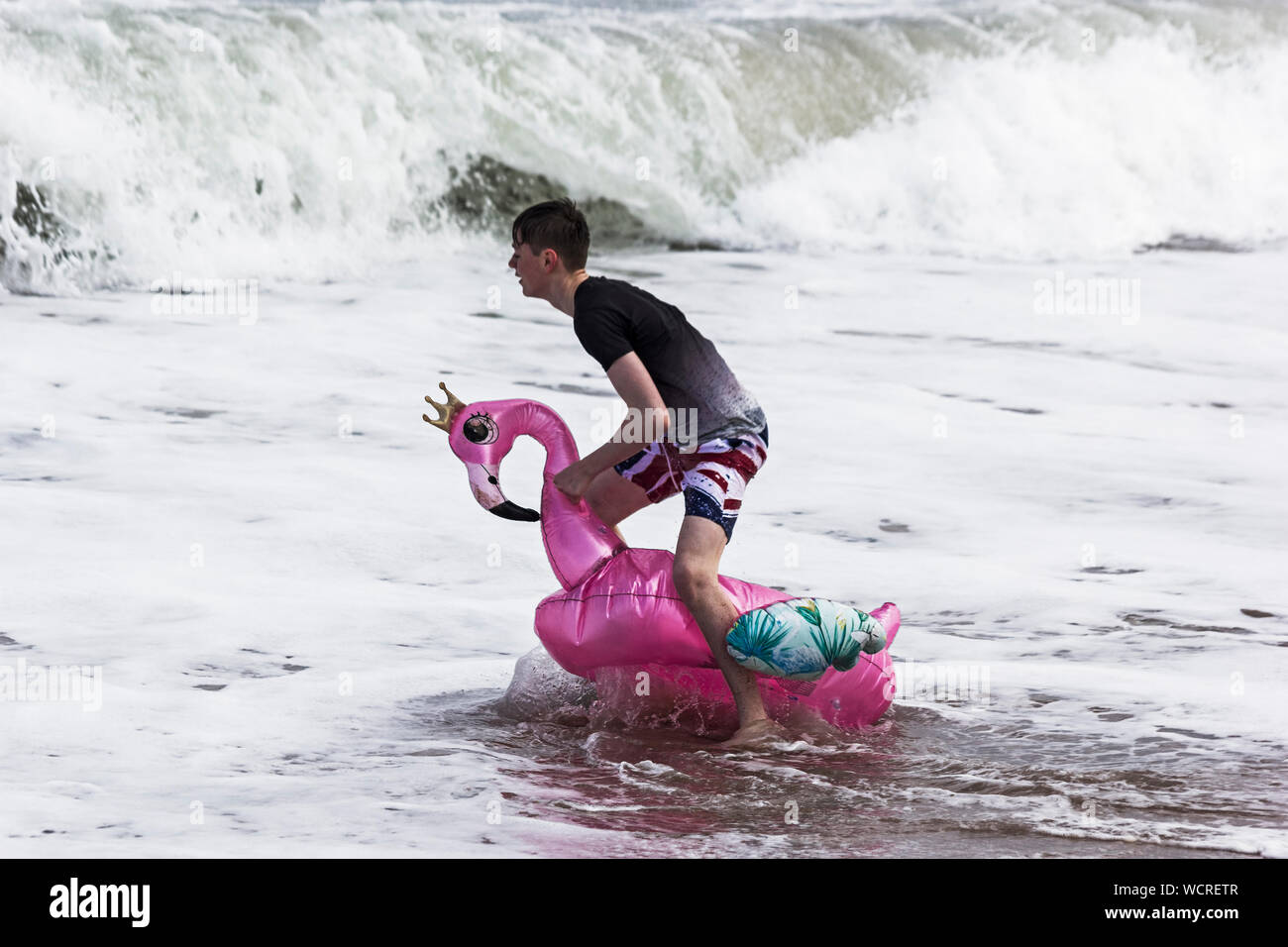 A boy heads into surf with an inflatable Stock Photo - Alamy