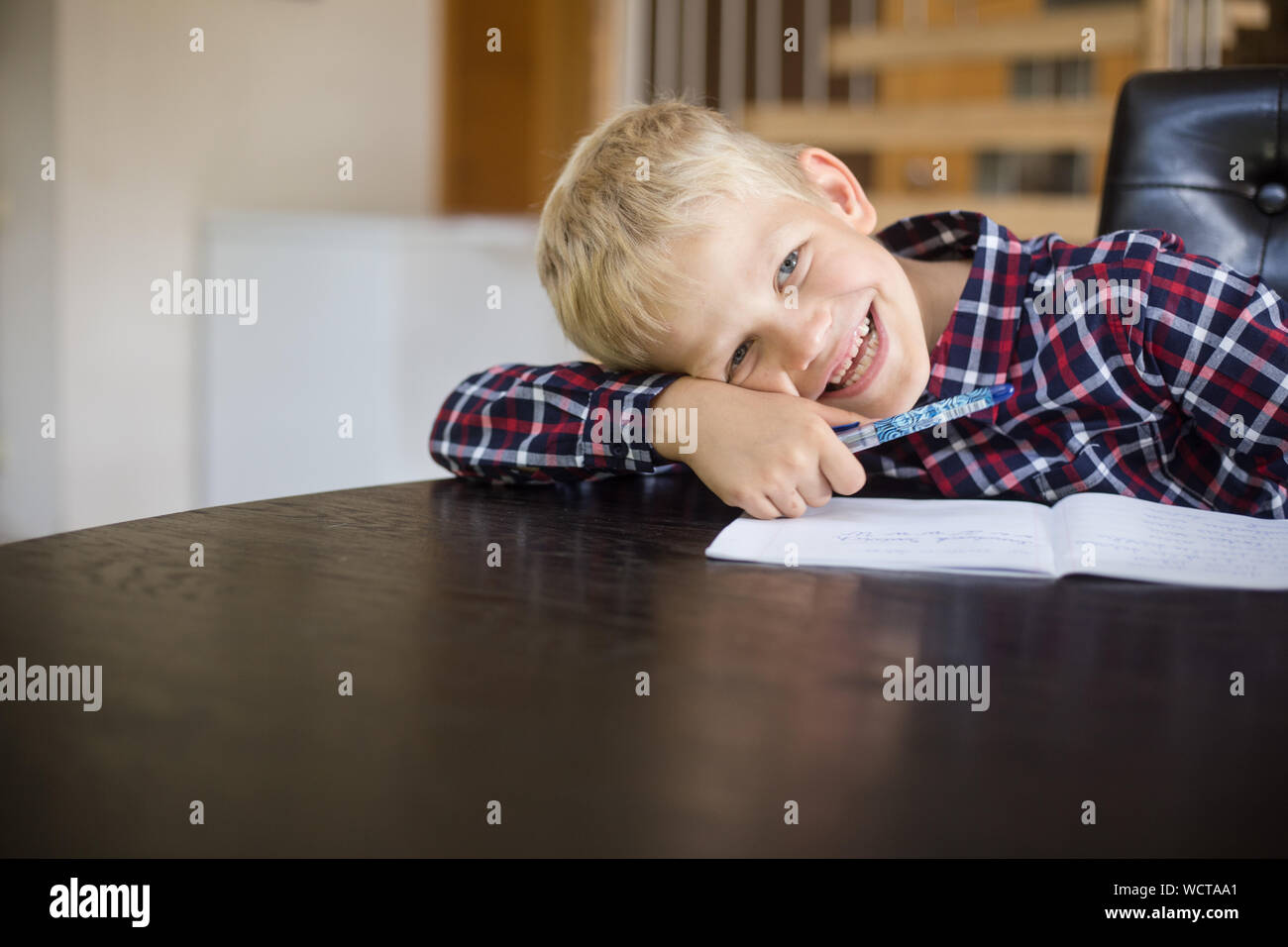 Happy schoolboy writing to notebook at home. Homework. Education ...