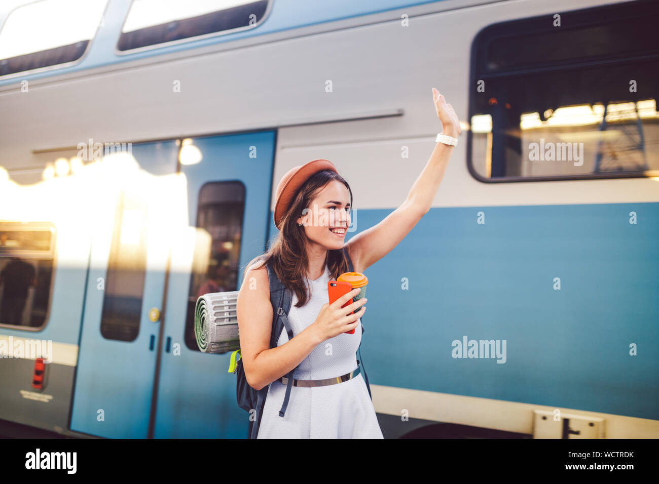 backpack traveler woman waving hand at train station platform summer ...