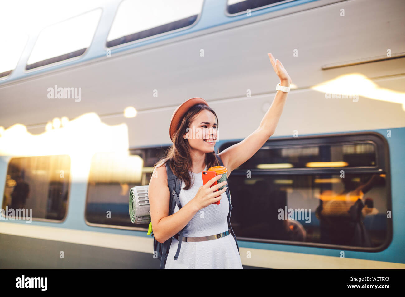 backpack traveler woman waving hand at train station platform summer ...