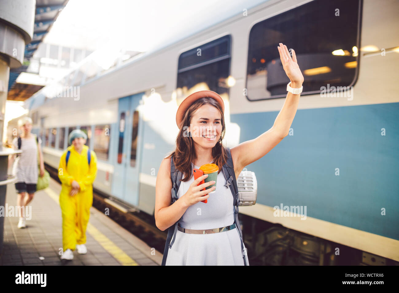 backpack traveler woman waving hand at train station platform summer ...
