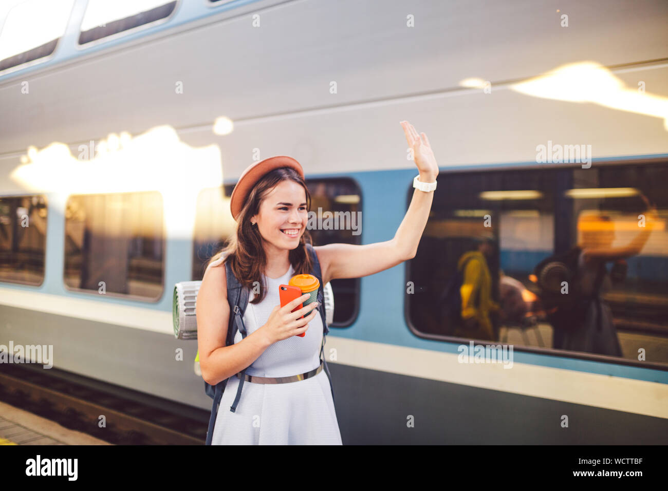 backpack traveler woman waving hand at train station platform summer ...