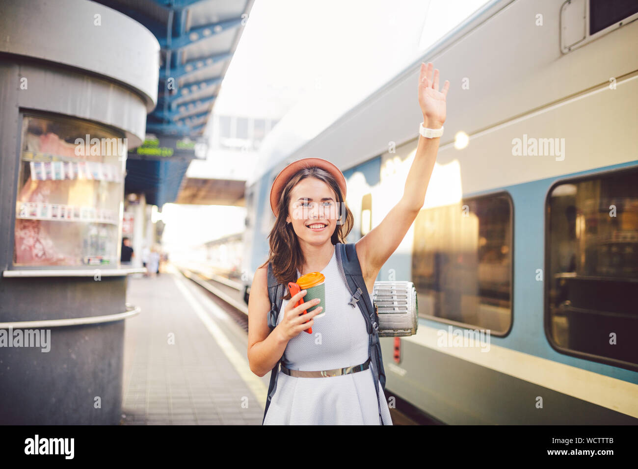 backpack traveler woman waving hand at train station platform summer ...