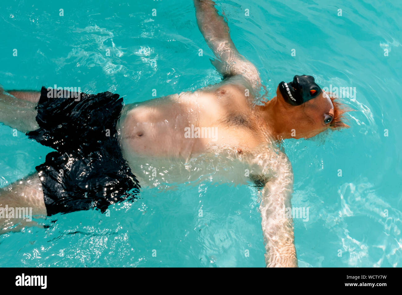 horse man is relaxing while on floating on the swimming pool water ...