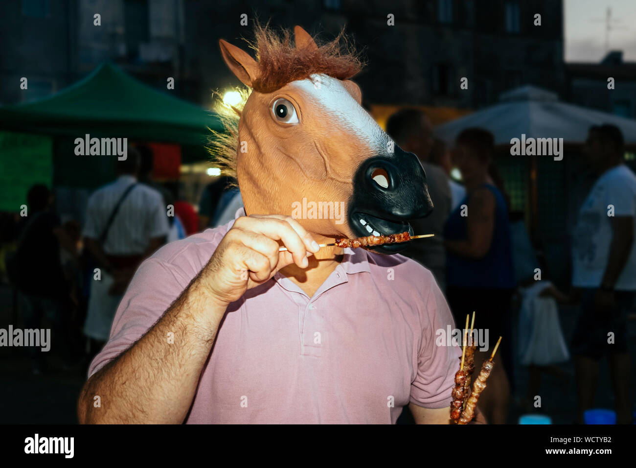 horse-man eating tasty bbq meat at a village festival in the evening ...