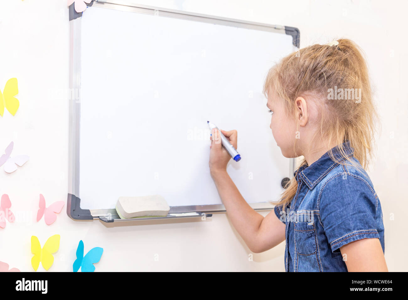 Little girl writing on board with a marker. Learning and school concept ...